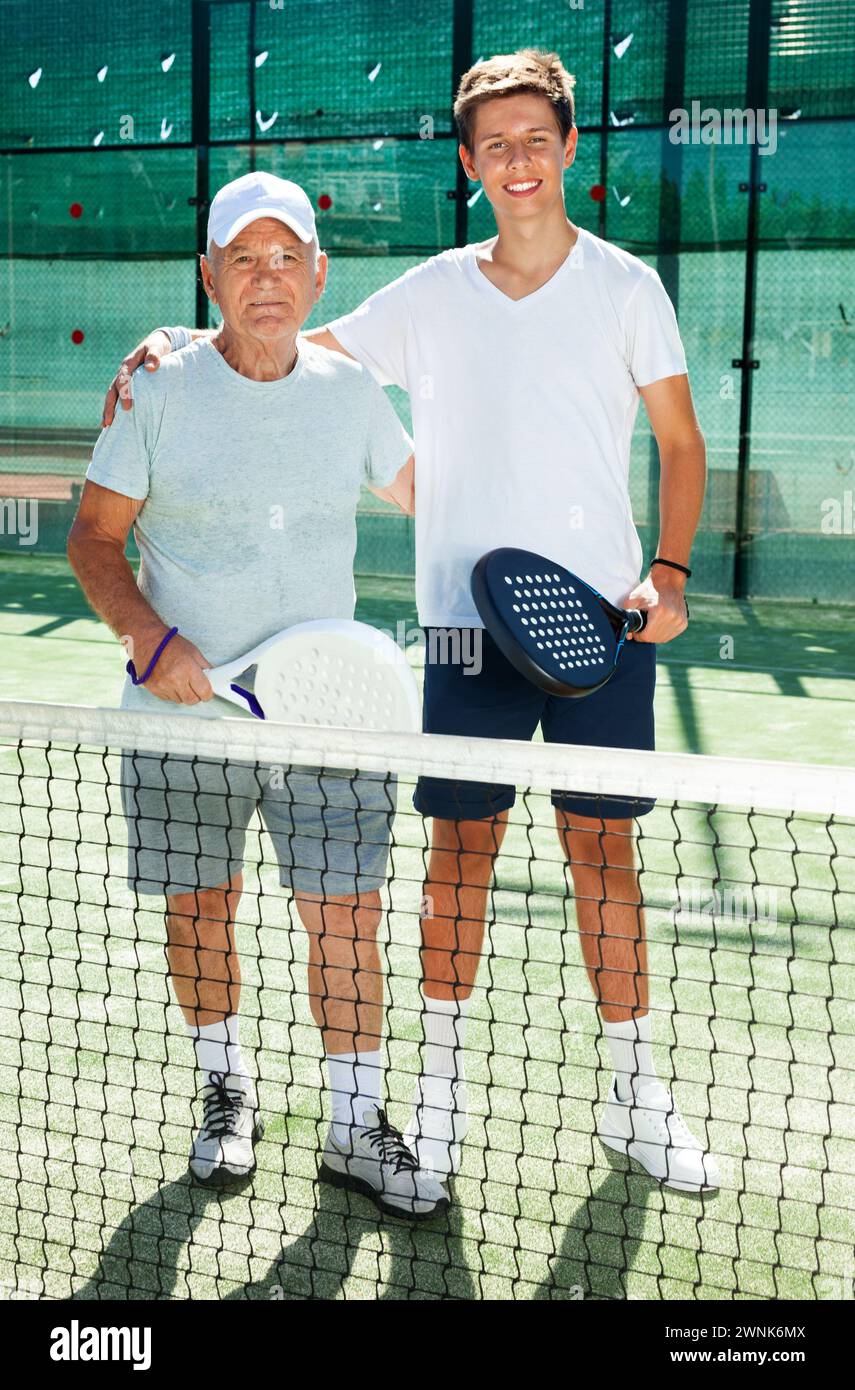 Senior man and young man posing on padel court Stock Photo - Alamy