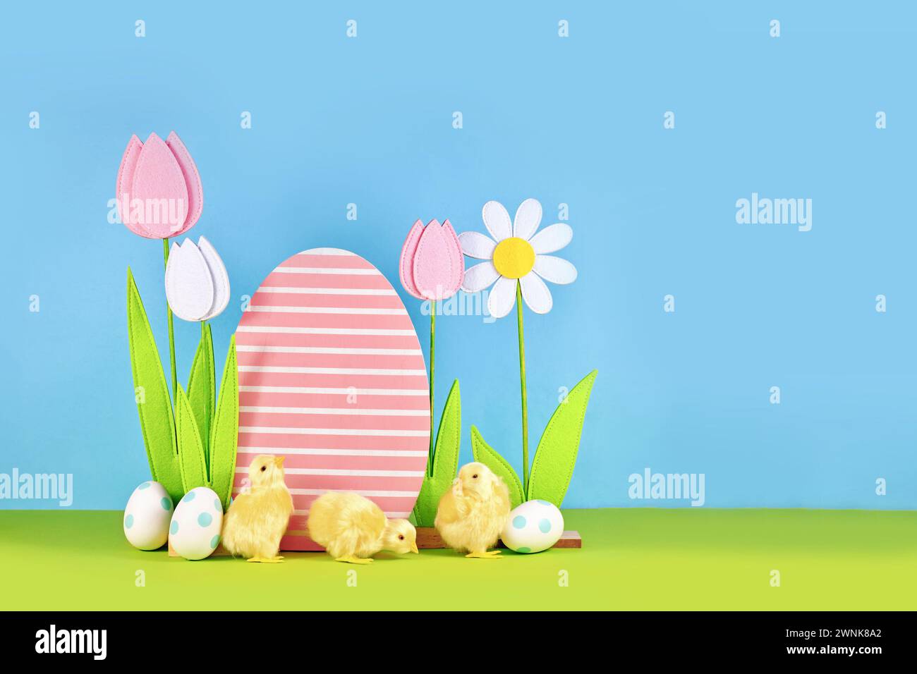 Spring flowers and wooden Easter egg with chicks in front of blue ...
