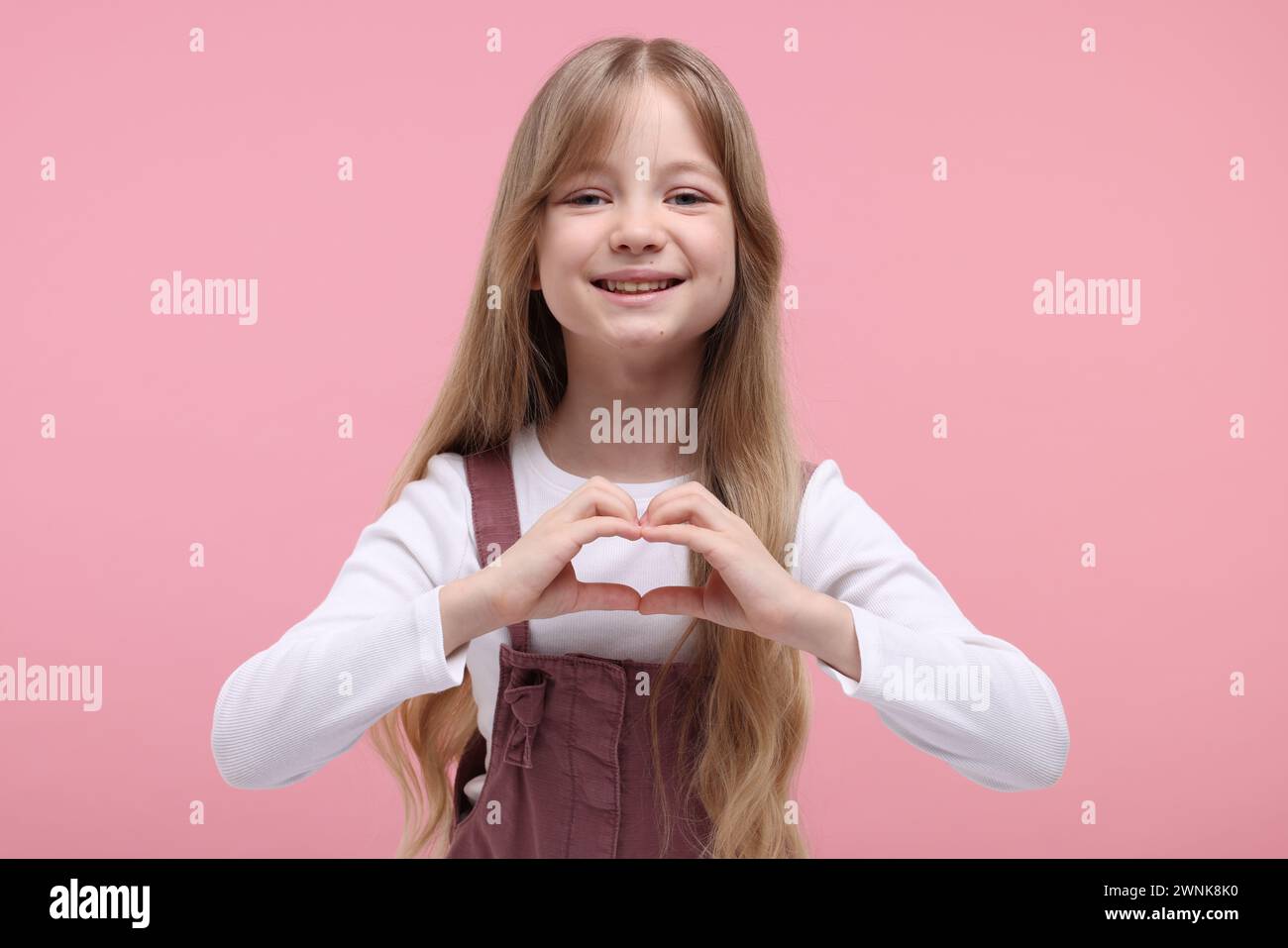 Happy girl showing heart gesture with hands on pink background Stock ...
