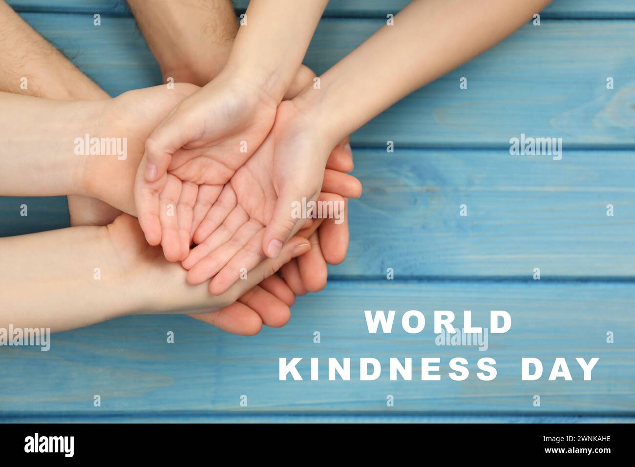 World Kindness Day. Parents and kid holding hands on light blue wooden ...