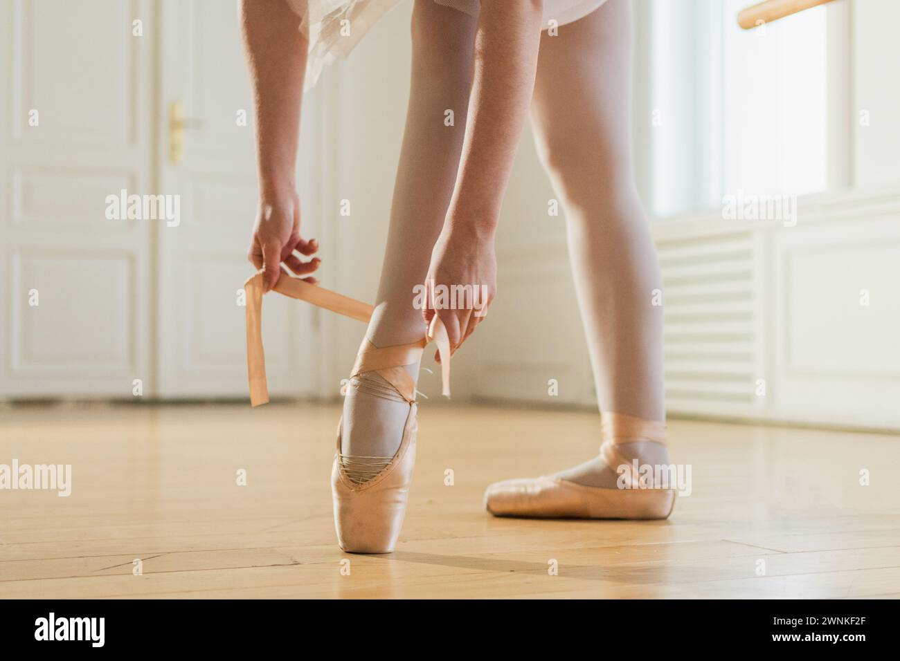 Ballerina puts on pointe shoes on leg in dance class. Classical ballet ...