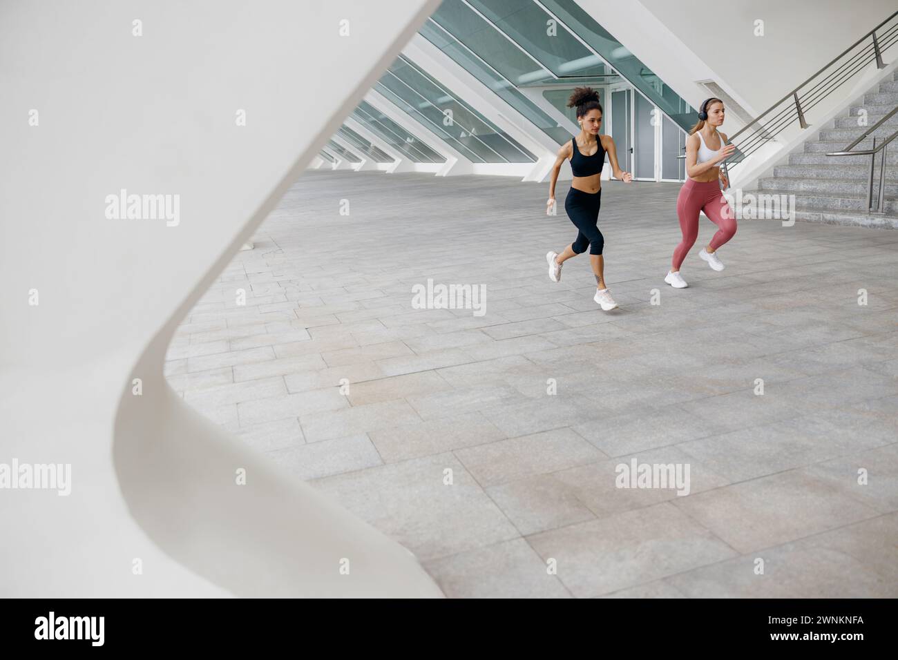 Two active women athlete running side by side along an outdoor track on ...