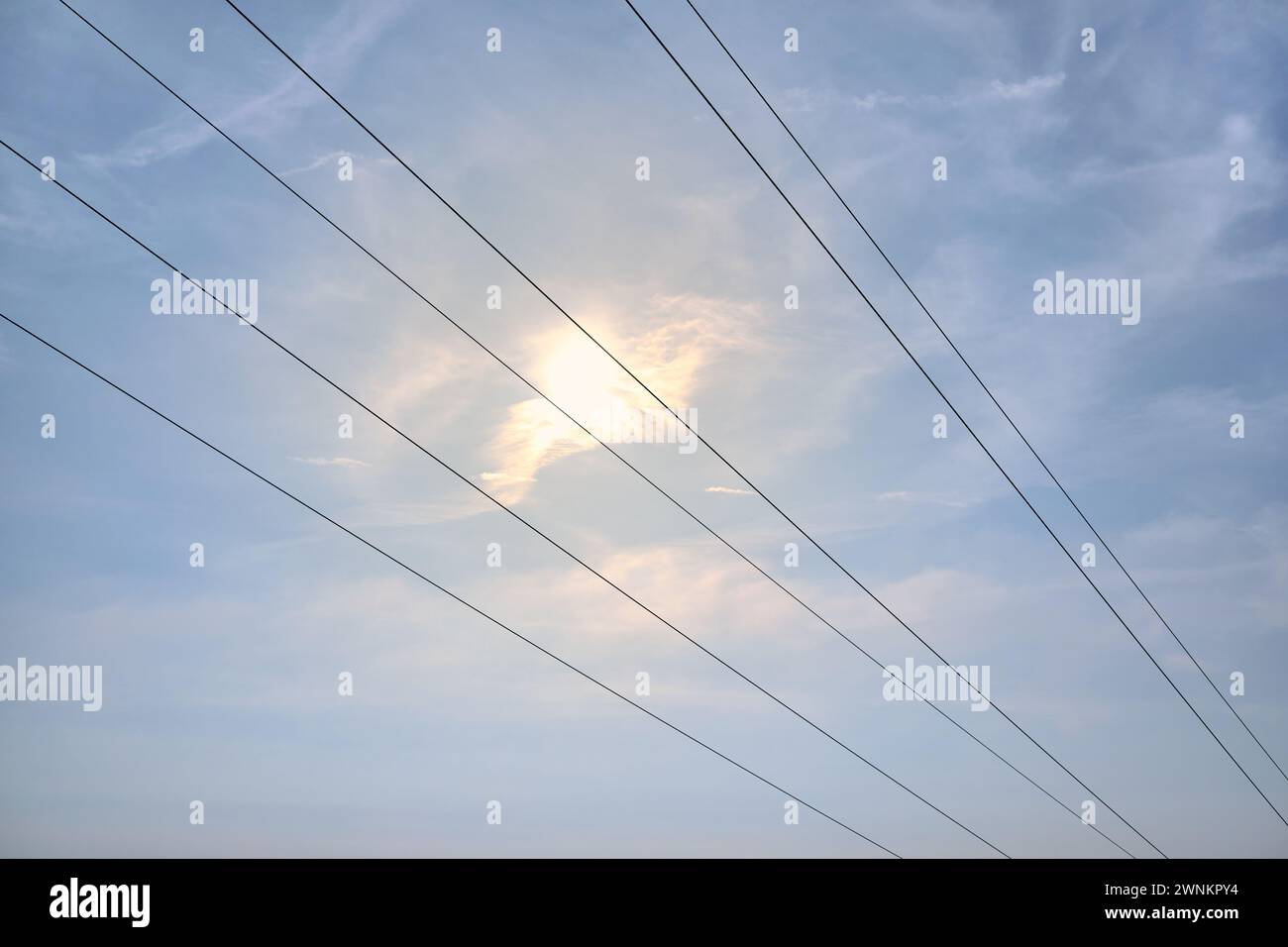 Diagonal hanging high-voltage transmission power lines against blue sky ...