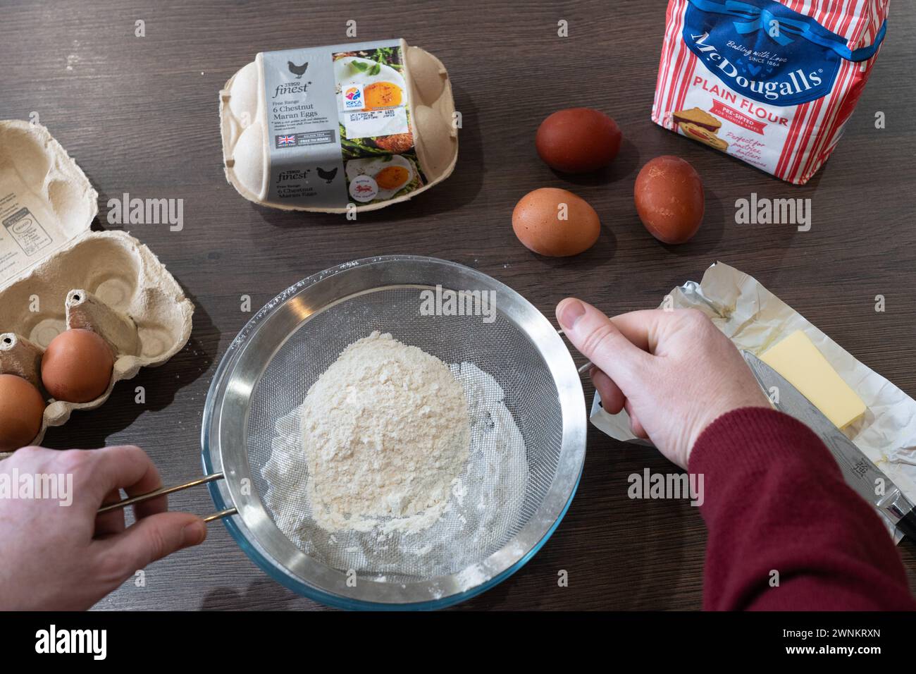A man's hands holding a sieve and sifting flour, with ingredients for ...