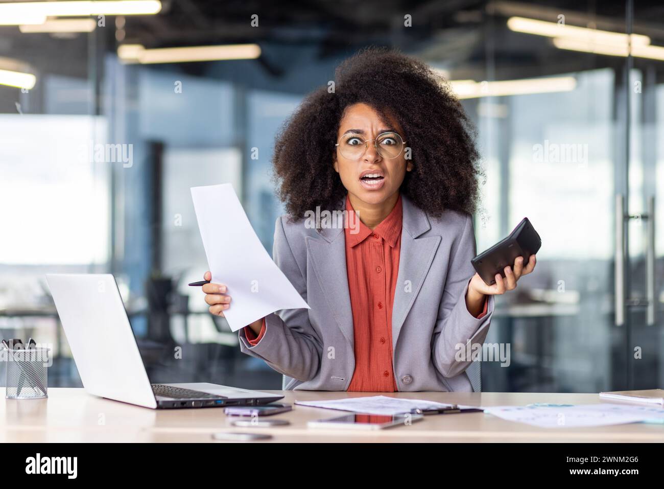 A frazzled businesswoman looks overwhelmed as she juggles paperwork and ...
