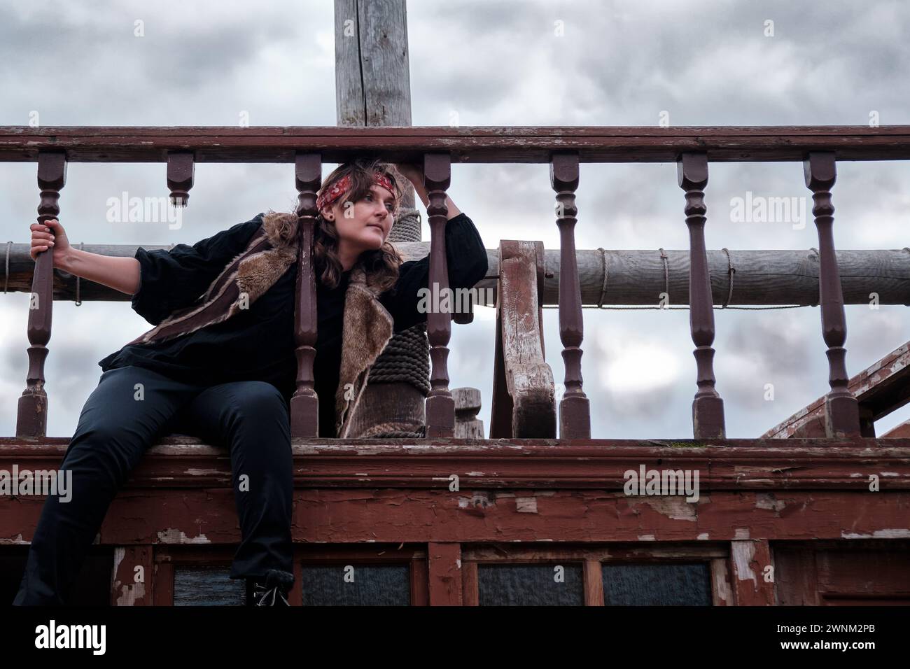 Pirate girl in gangster clothes sitting at the rail on the deck of a ...