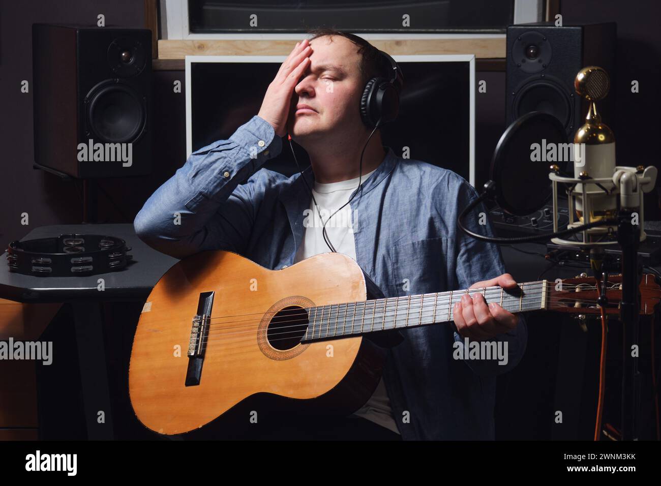 Sad musician holding his sore head in recording studio, losing his ...