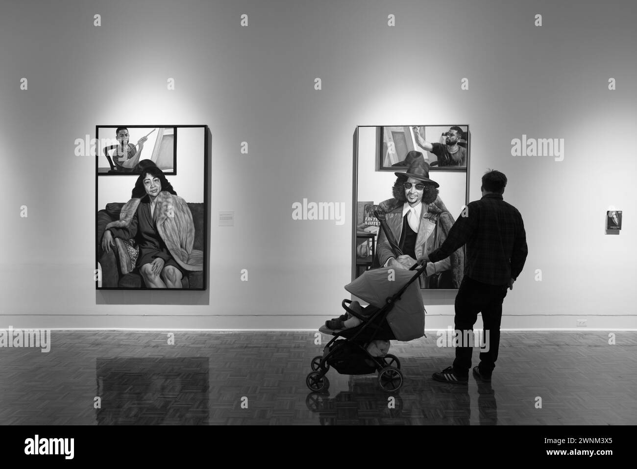 A man, with a baby in a stroller, looking at paintings of African ...