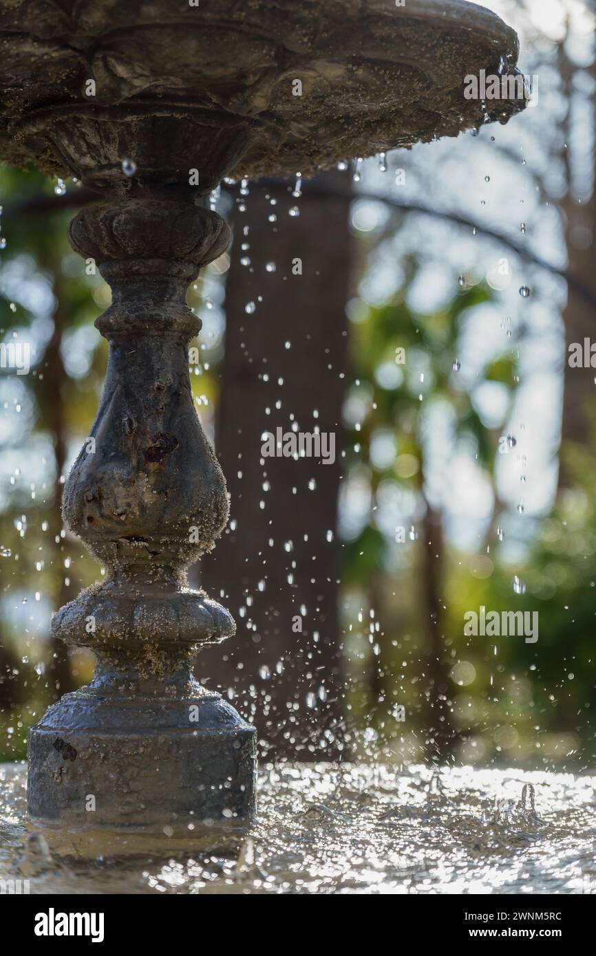 Profile view of a public fountain with splashing water, blue sky and ...