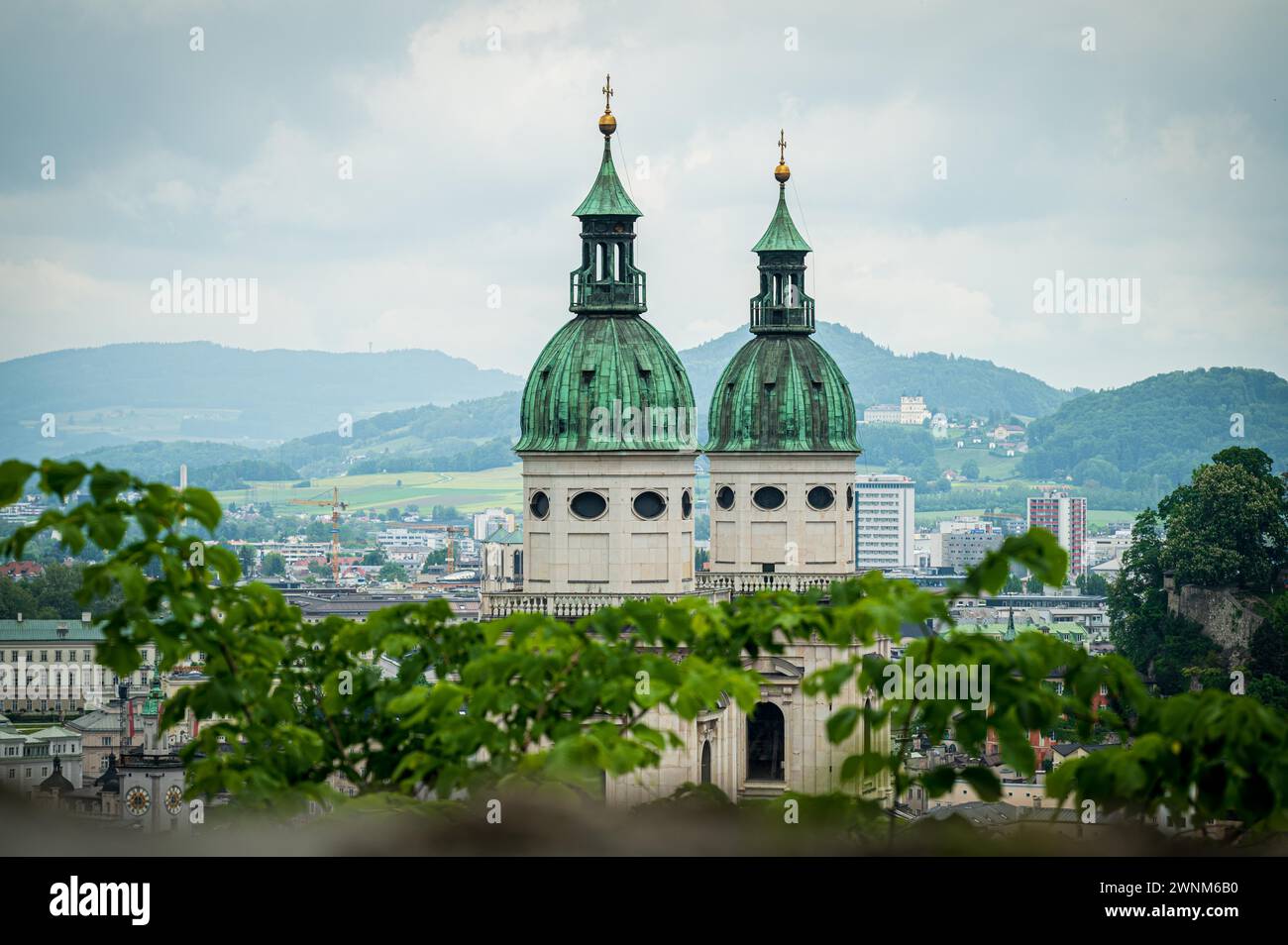 Two church towers with green roofs, framed by leaves, landscape in the ...