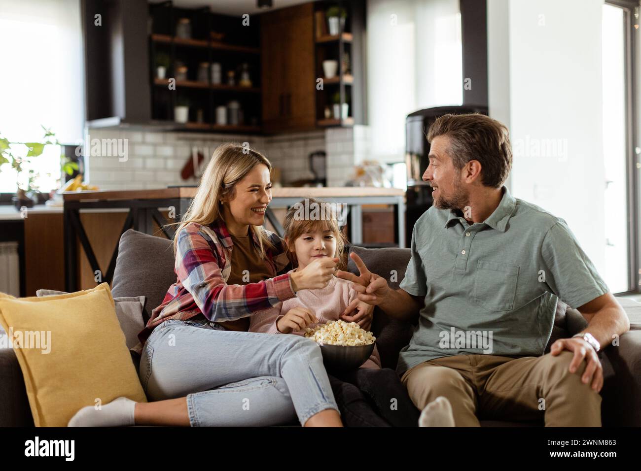 A joyful family lounges on the sofa, engaging in playful conversation ...