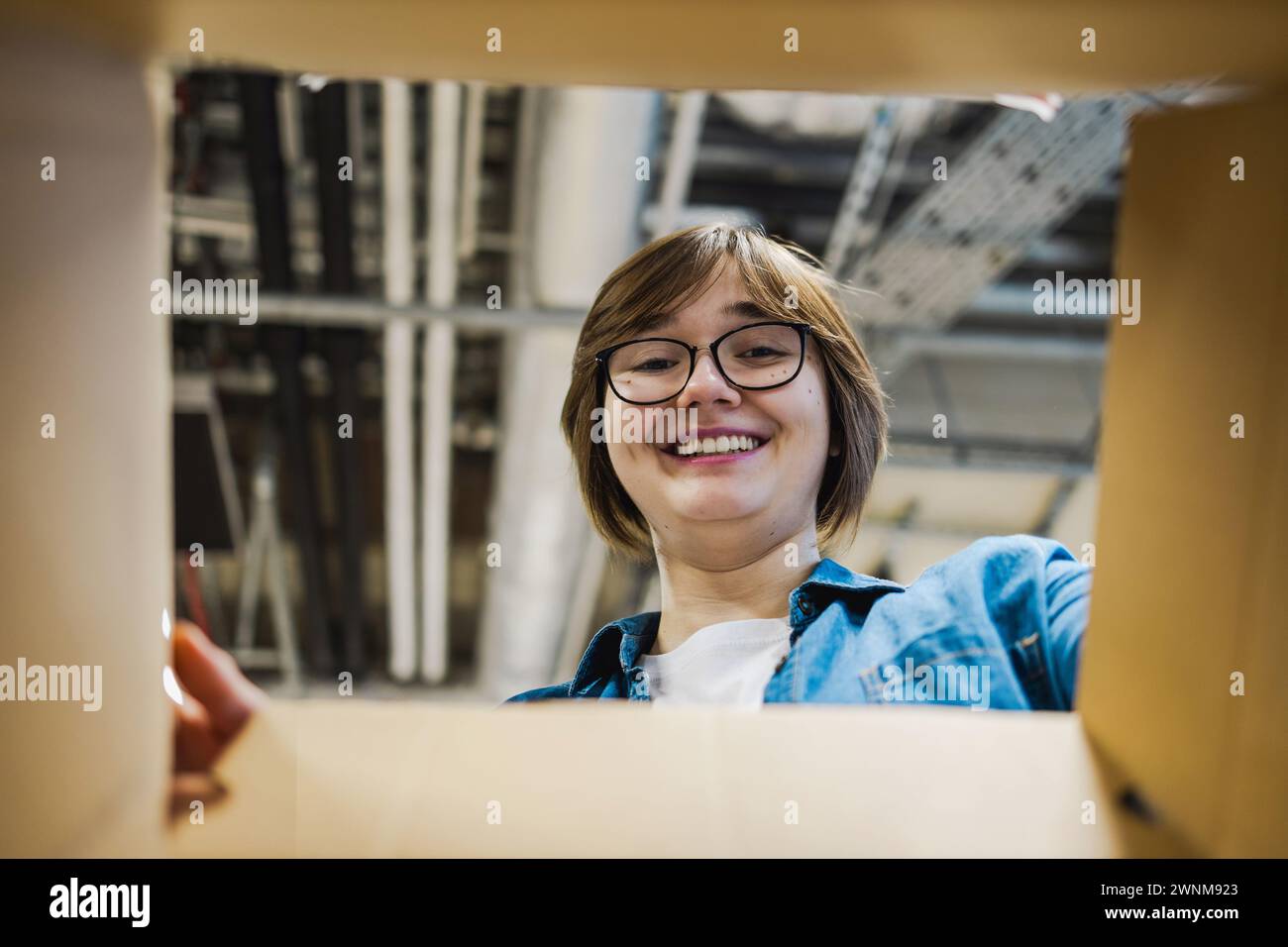 Warehouse female worker looking through an empty box Stock Photo - Alamy