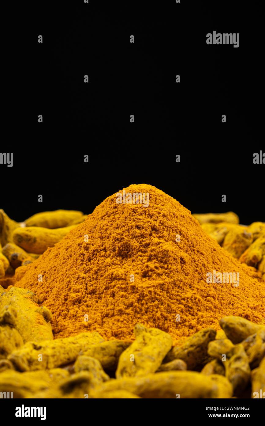 Turmeric powder and dried turmeric root on a black background Stock ...
