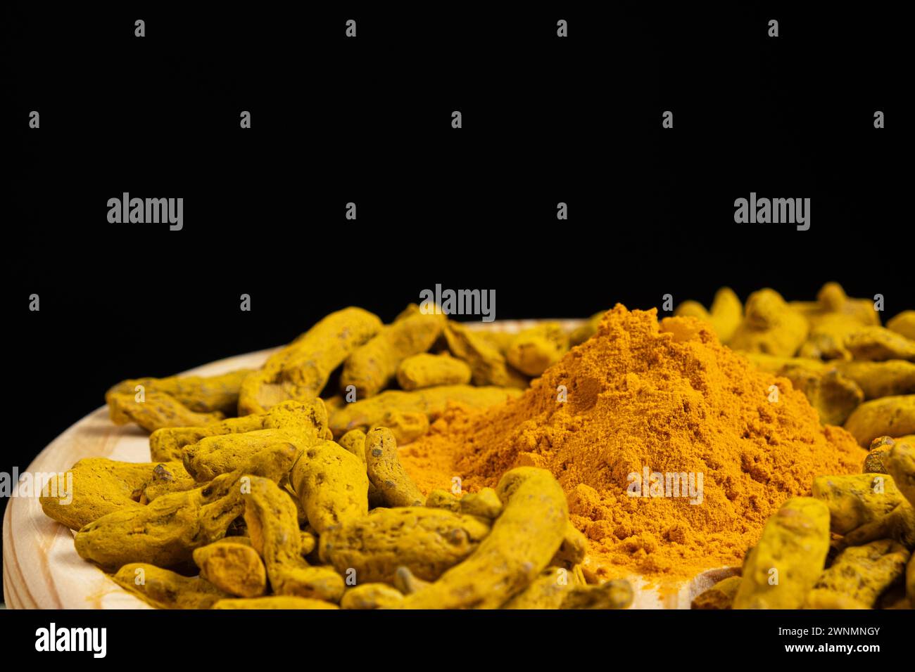 Turmeric powder and dried turmeric root on a black background Stock ...