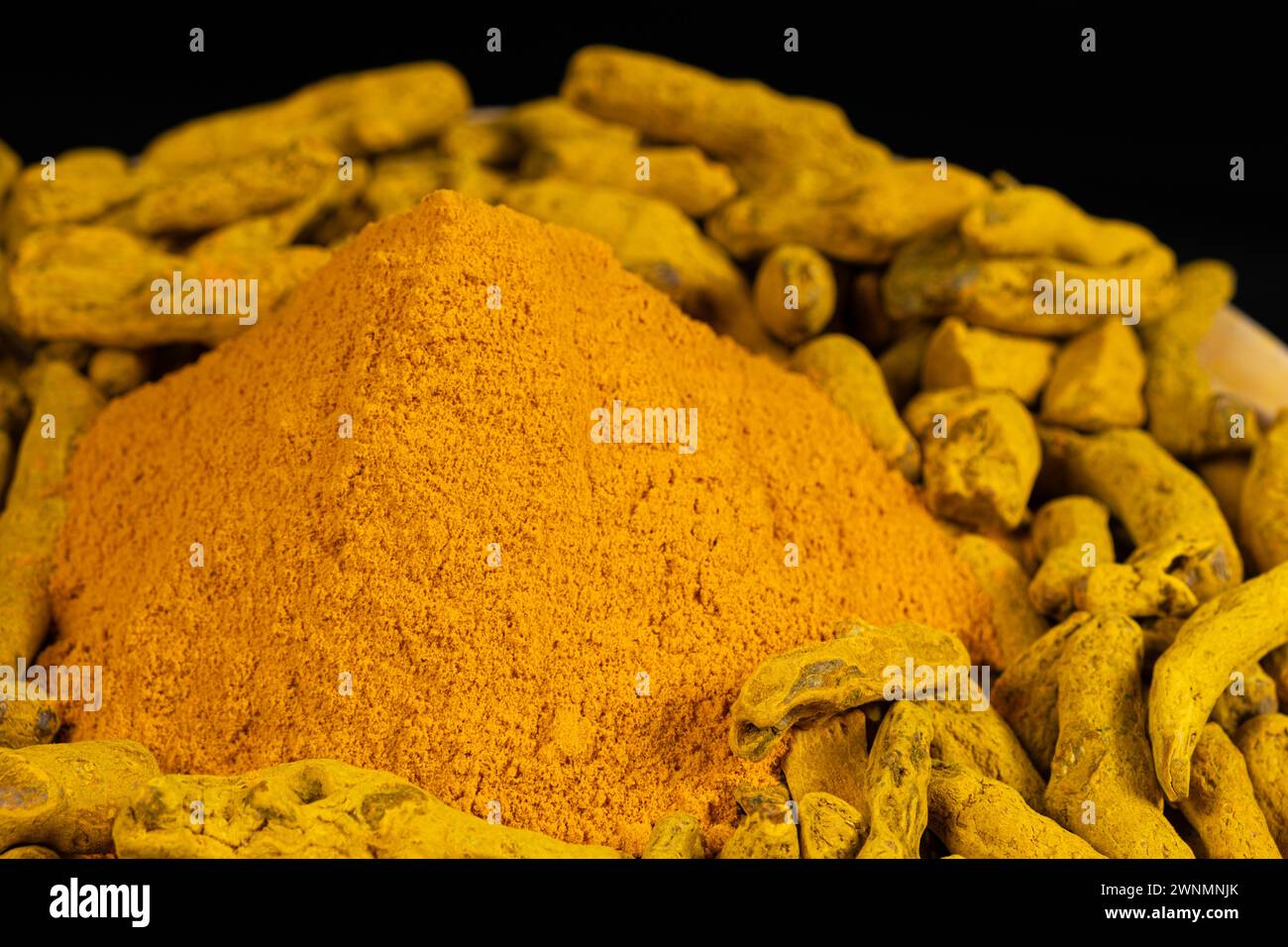 Turmeric powder and dried turmeric root on a black background Stock ...