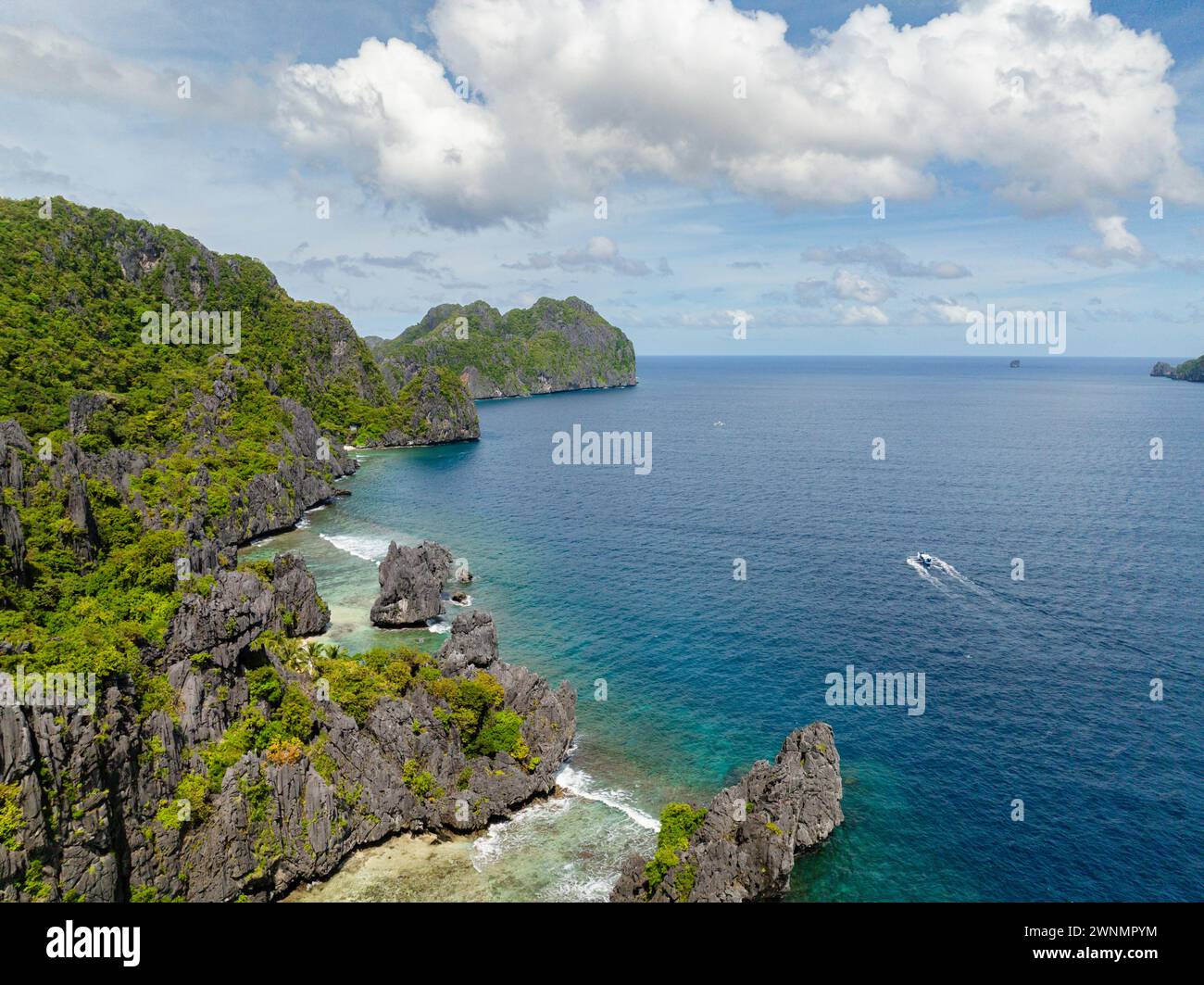 Coastline wiith limestone rocks and boat over the blue sea. Matinloc ...