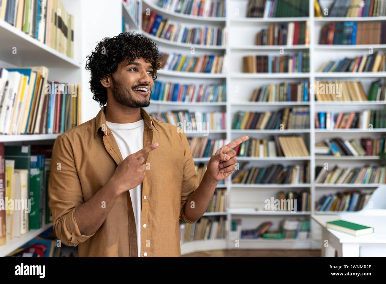A person stands in a library, surrounded by shelves lined with books ...