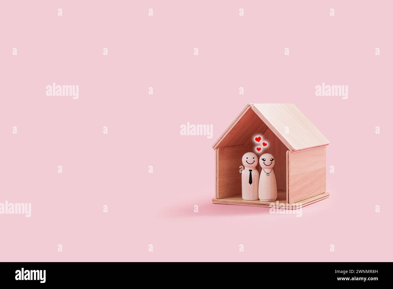 Happy wooden male and female figures inside a tiny wooden house ...