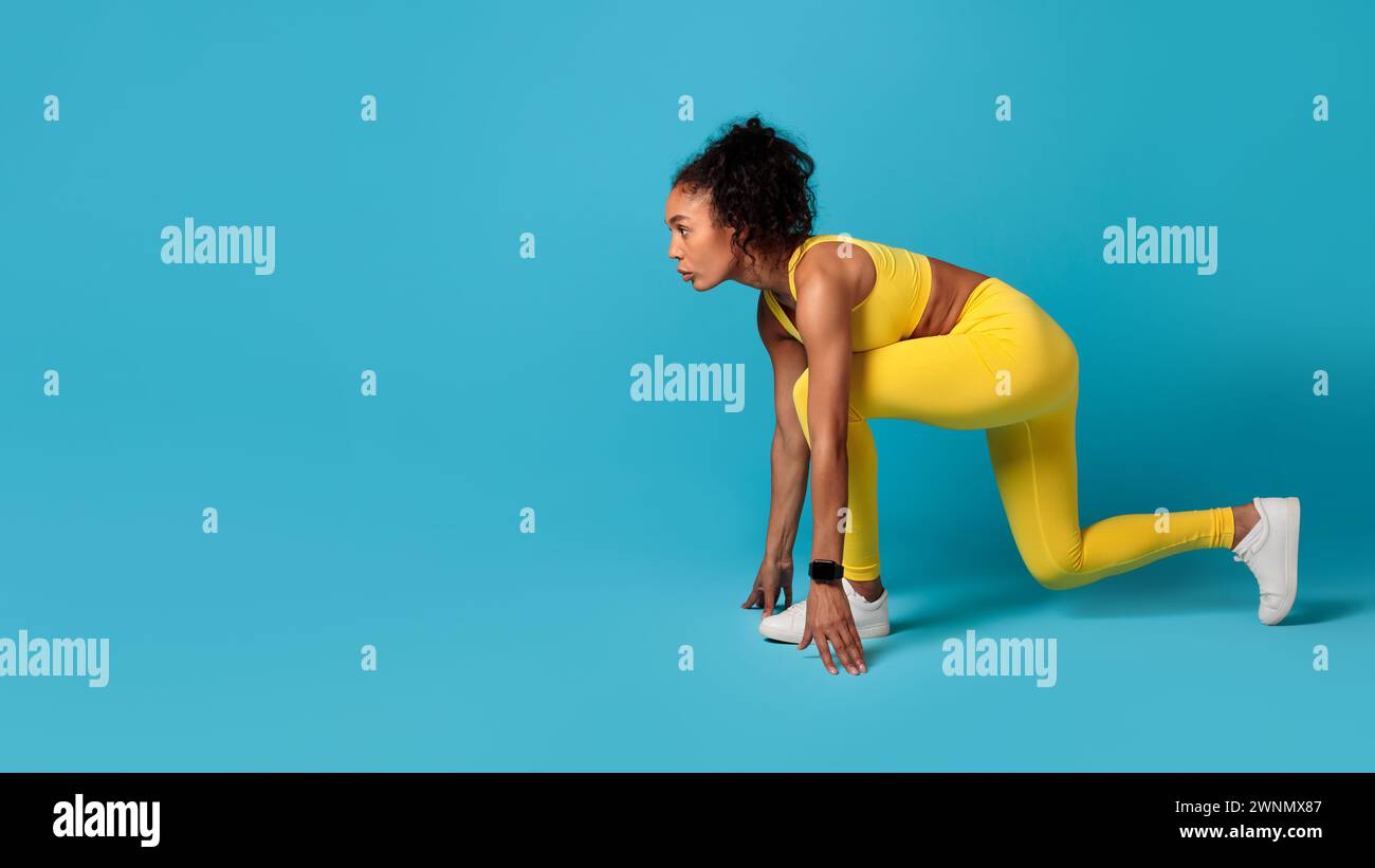 black woman confidently posing in crouch position on blue background ...