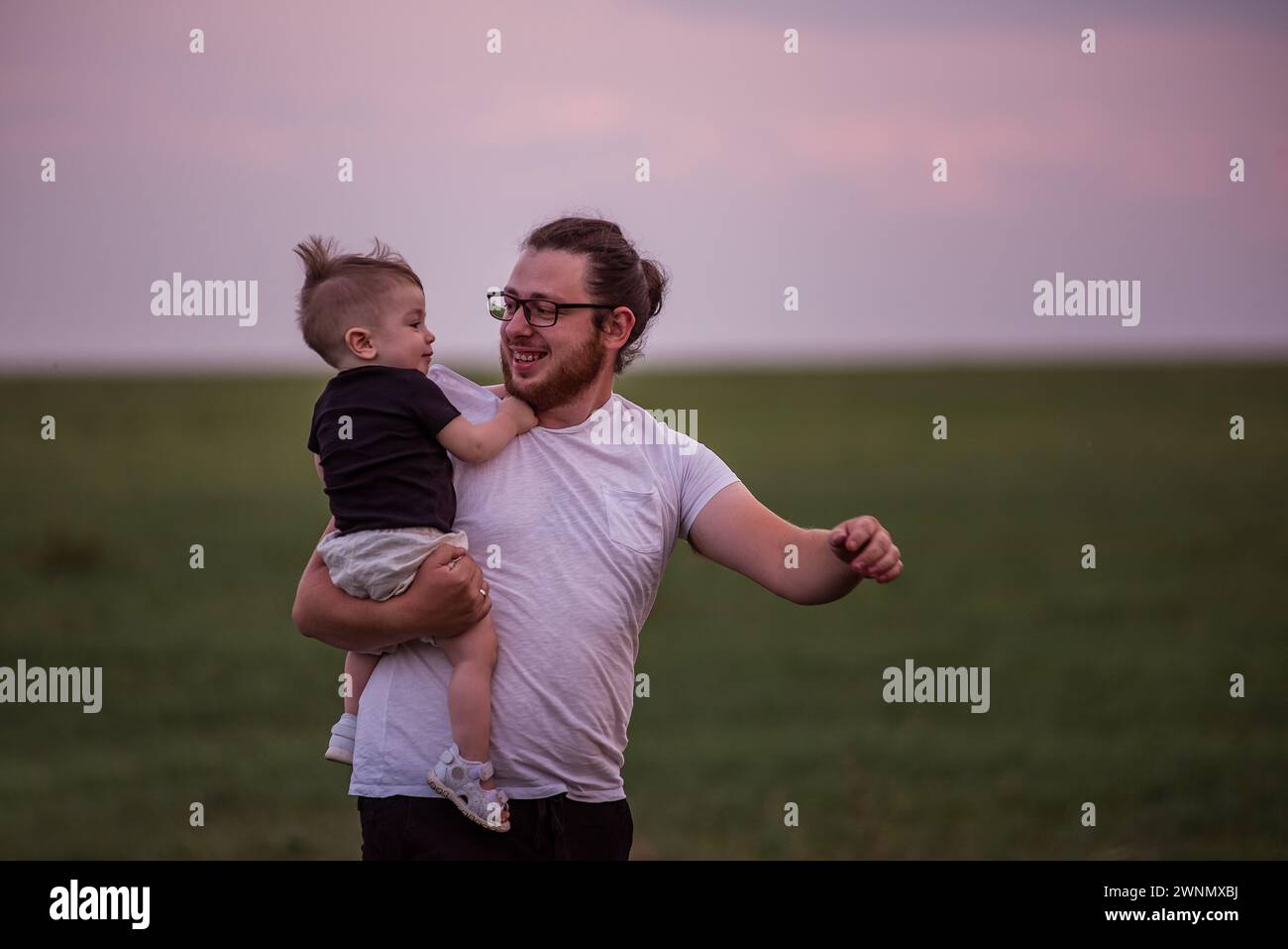 Heartwarming scene of diversity father carrying smiling son on ...