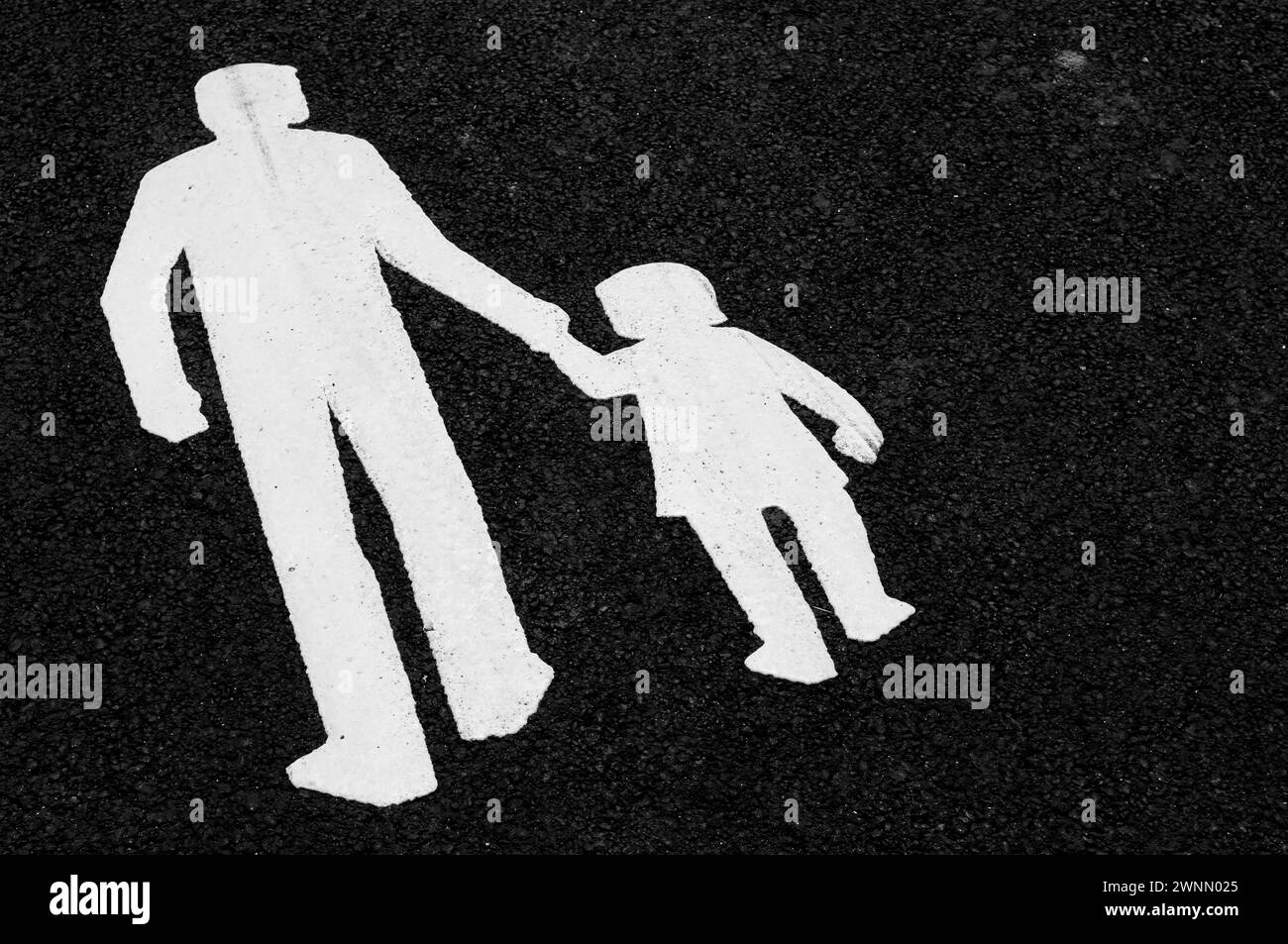A pedestrian crossing sign consisting of two white figures, an adult ...