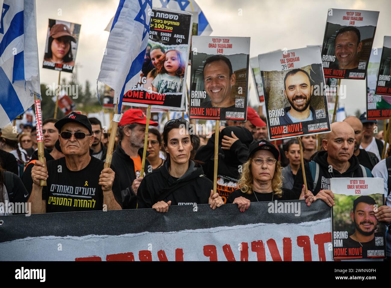 Israeli hostage families carry the photos of their loved ones who are ...