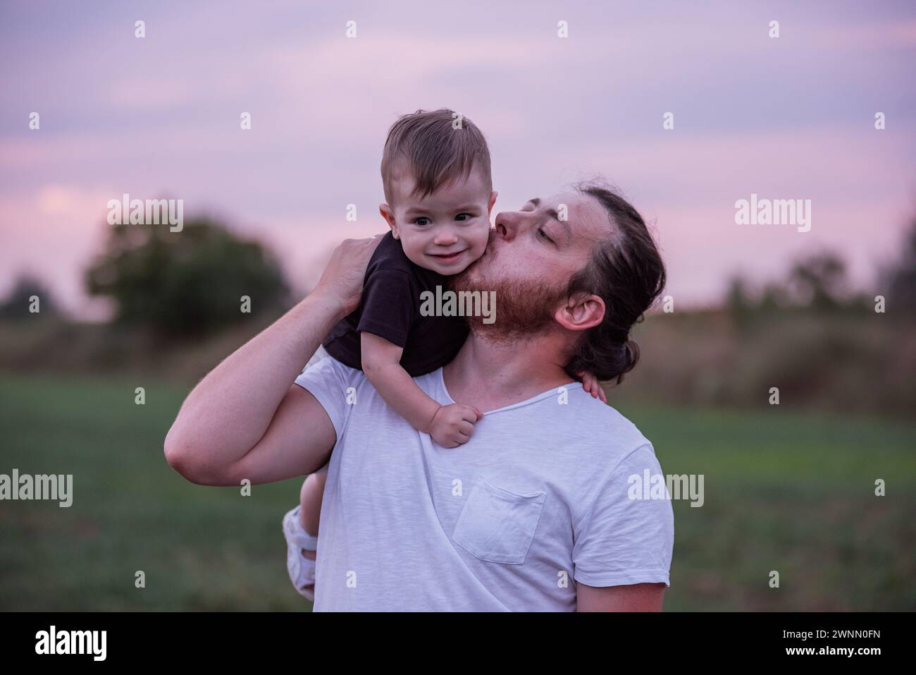 Heartwarming scene of diversity father carrying smiling son on ...