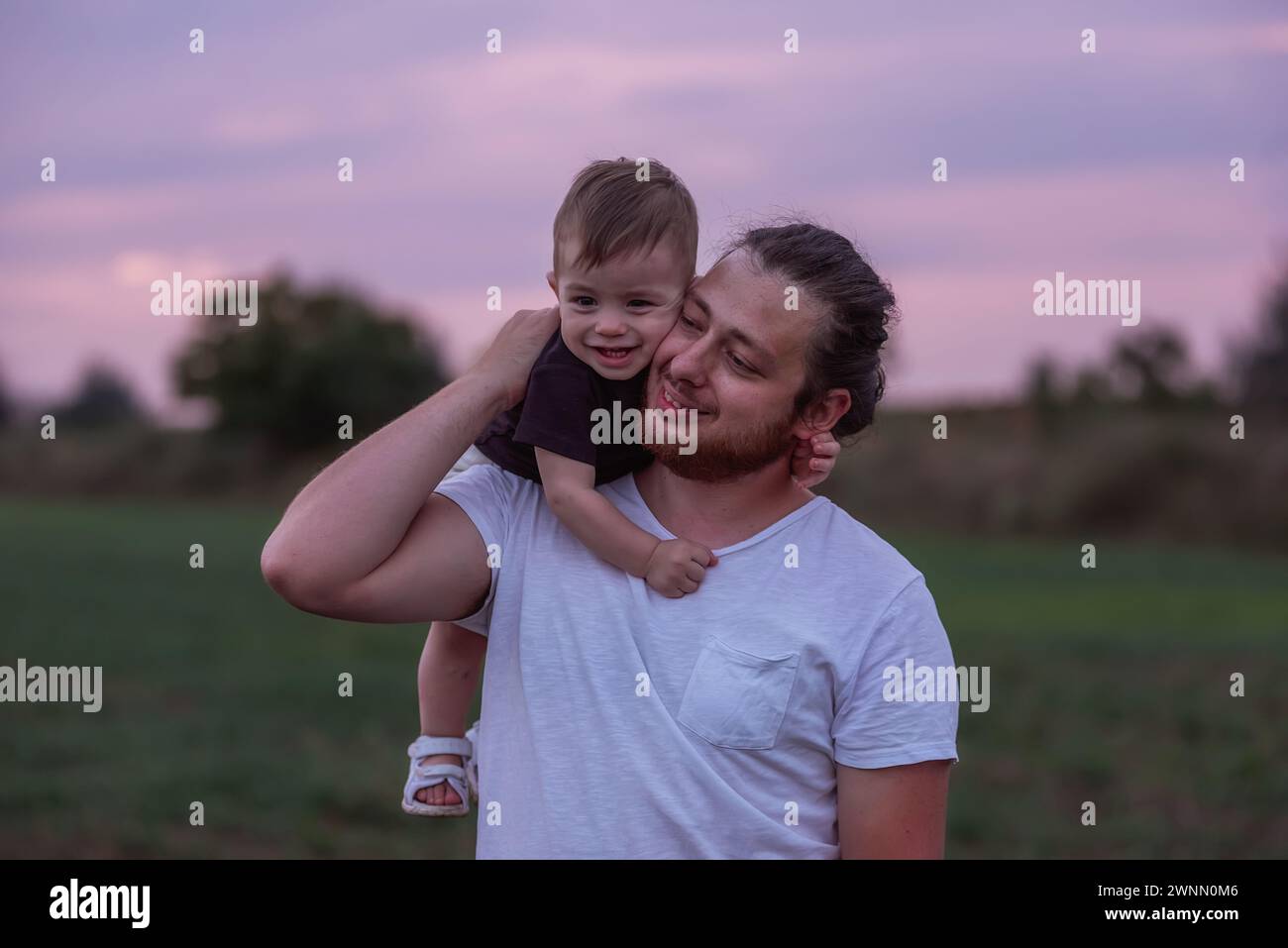 Heartwarming scene of diversity father carrying smiling son on ...
