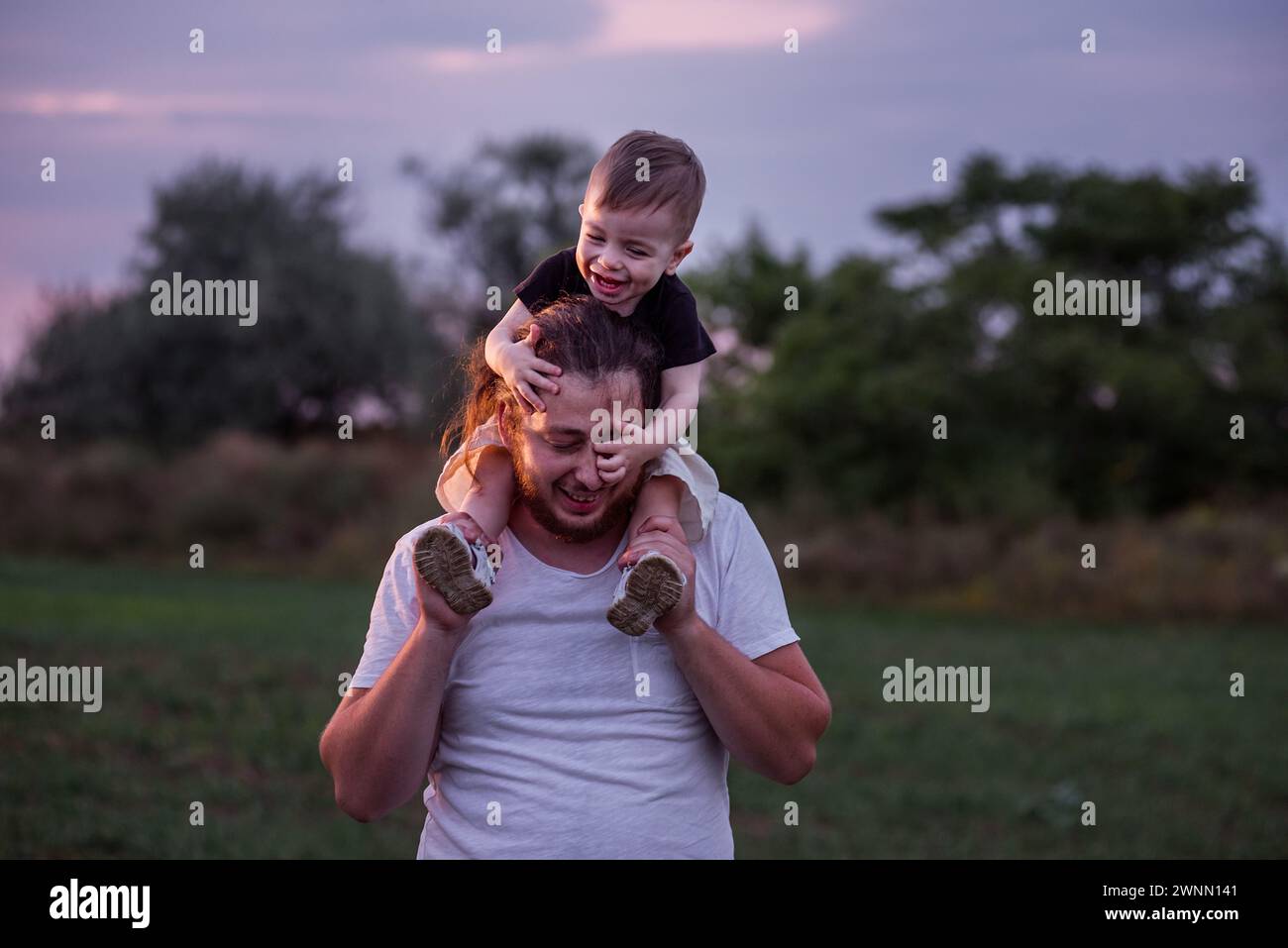 Diversity father with beard carrying son on shoulders shares tender ...