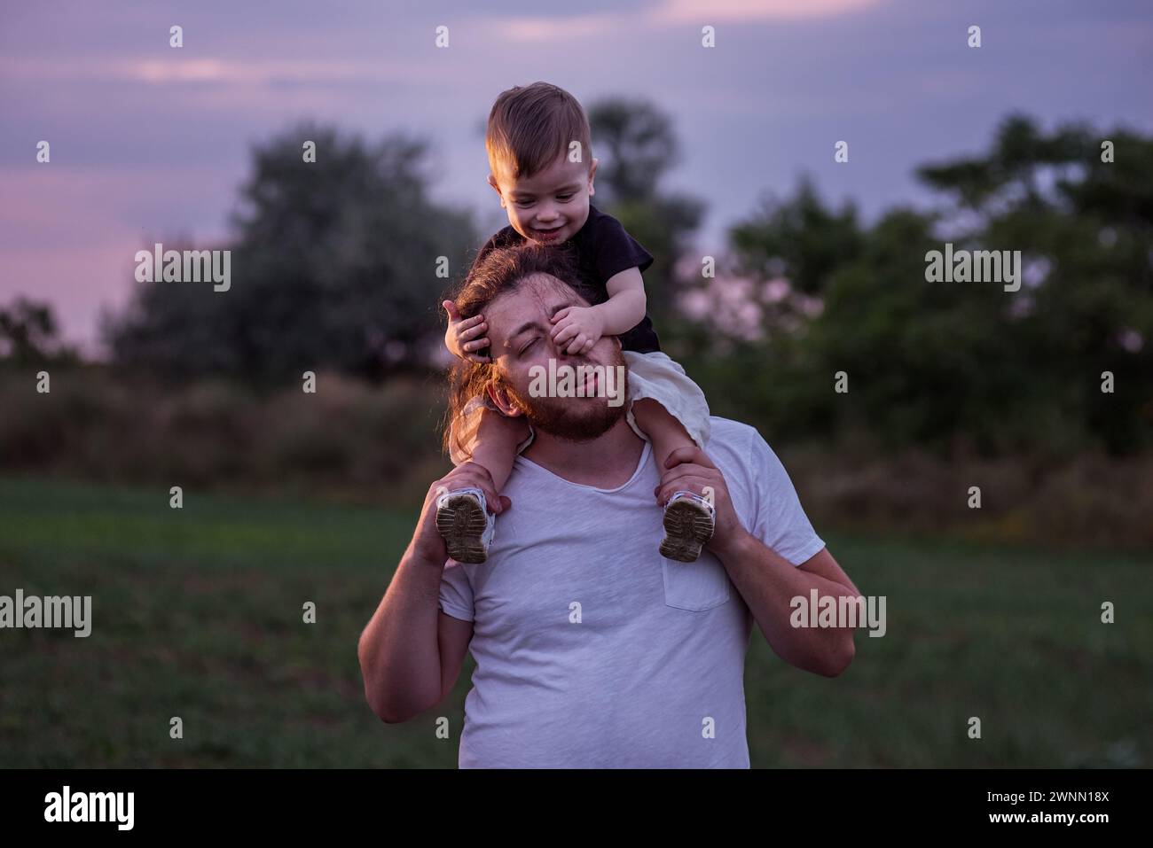 Diversity father with beard carrying son on shoulders shares tender ...