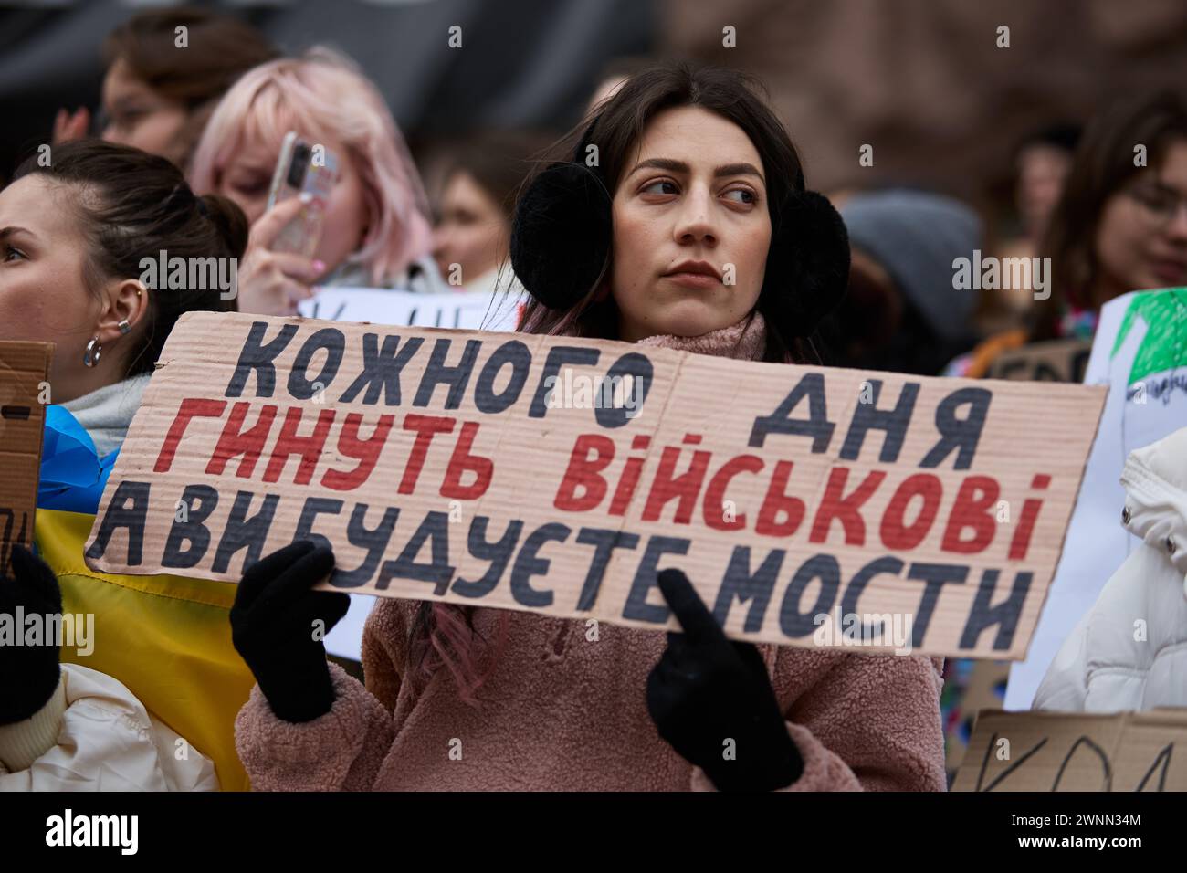 Ukrainian activist holds a banner "Soldiers die every day and you keep ...