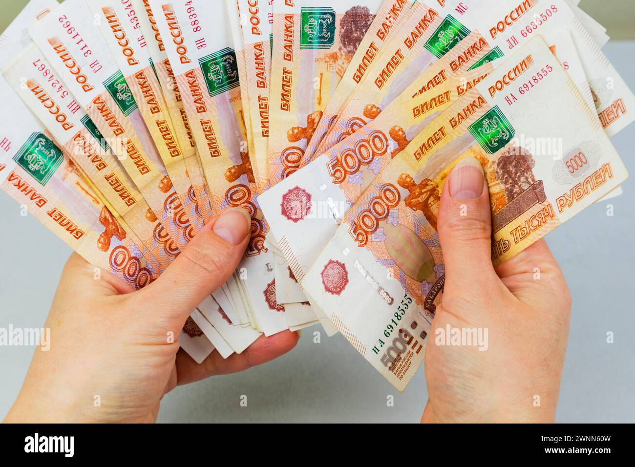 A woman holds a wad of money in her hand. A million Russian rubles in ...