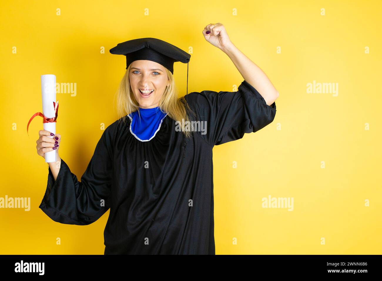 Beautiful blonde young woman wearing graduation cap and ceremony robe ...