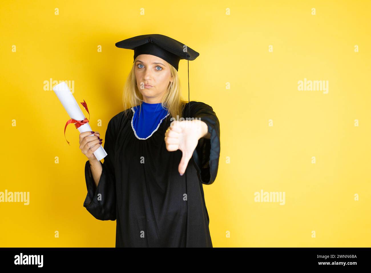 Beautiful blonde young woman wearing graduation cap and ceremony robe ...