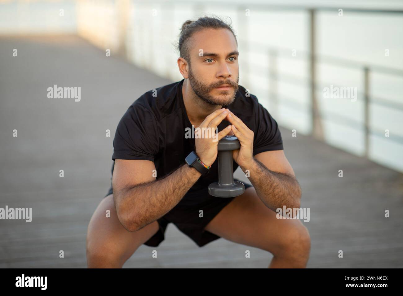 Athlete man performing squats holding dumbbell weights working out ...