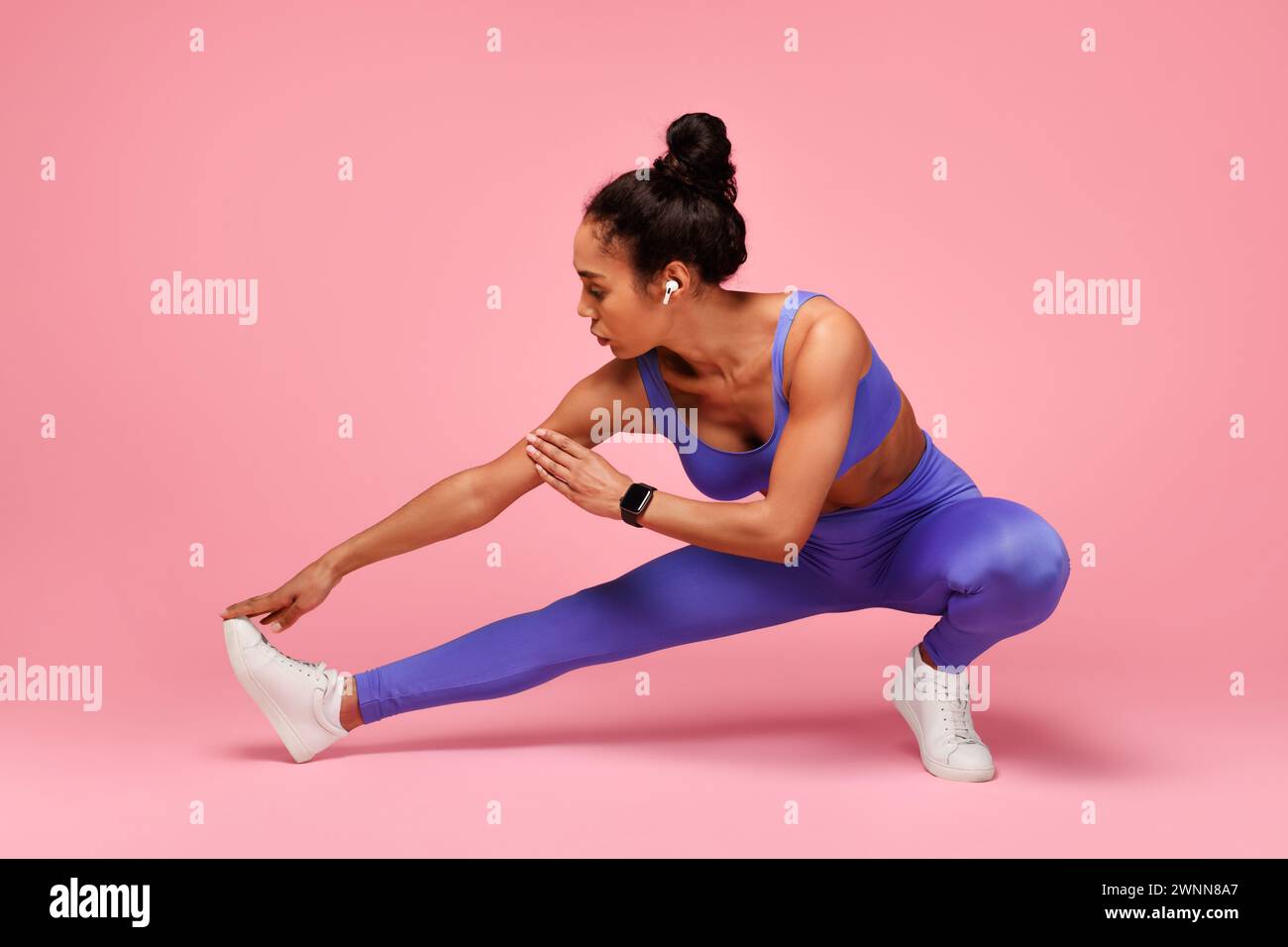 Black millennial woman showcases wellness and strength stretching legs ...