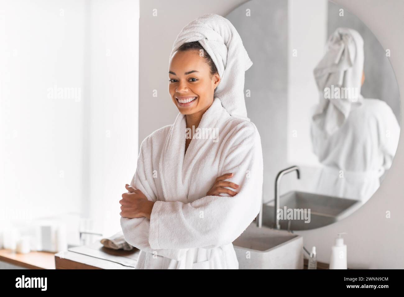 African American lady standing with folded arms in bathrobe indoors ...