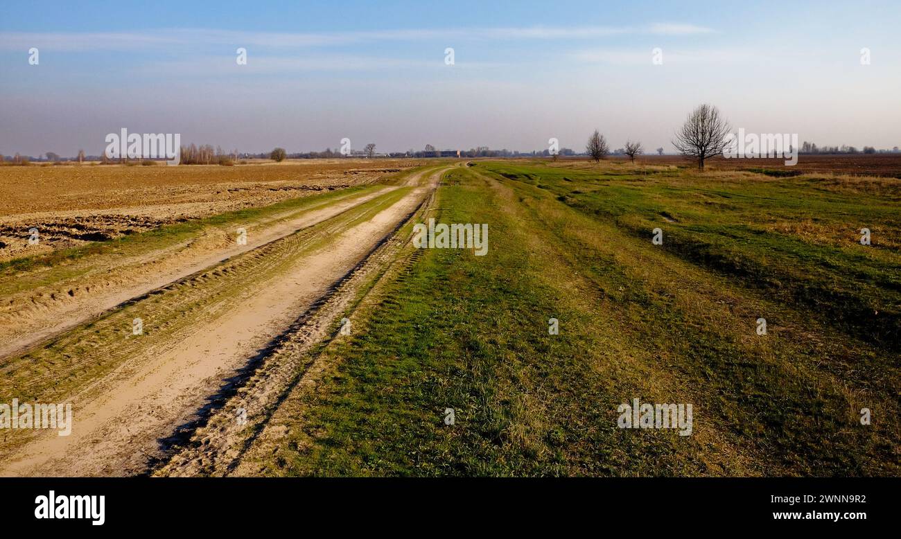 Clear skies oversee the tranquil scene of open fields cut through by a ...