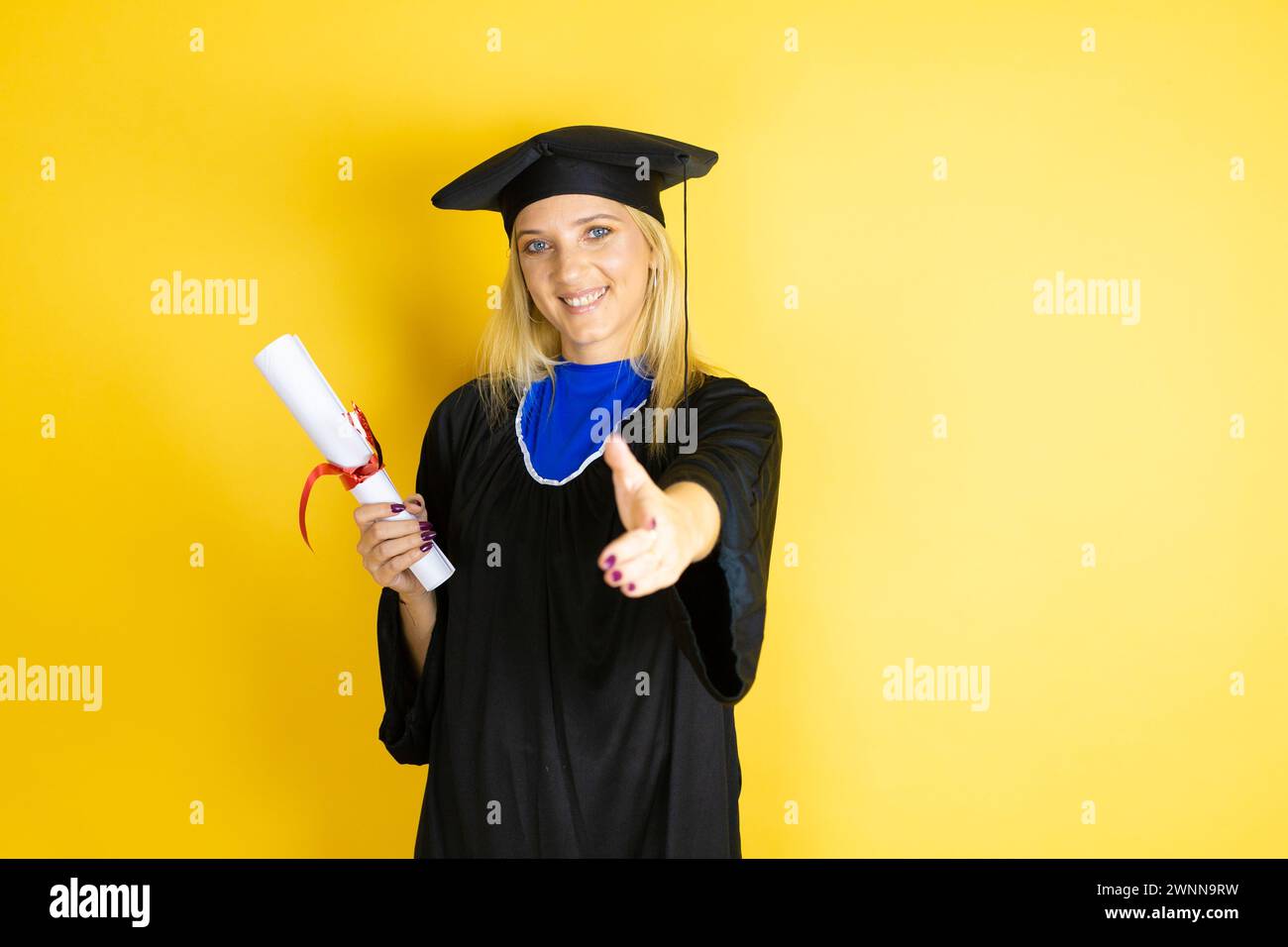 Beautiful blonde young woman wearing graduation cap and ceremony robe ...