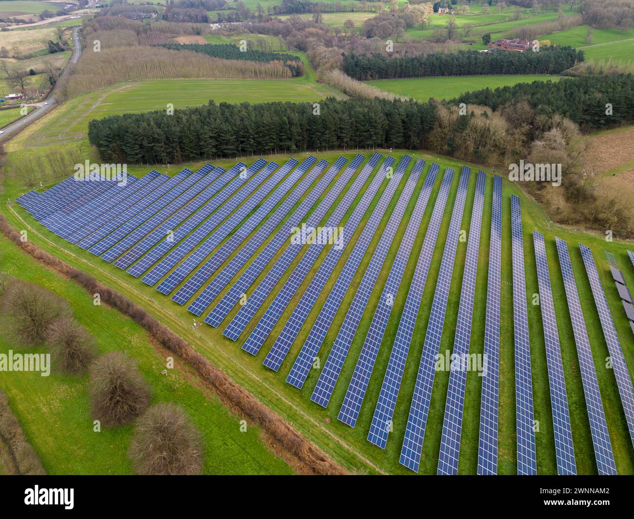 Drone shot capturing a vast solar panel farm amidst greenery ...