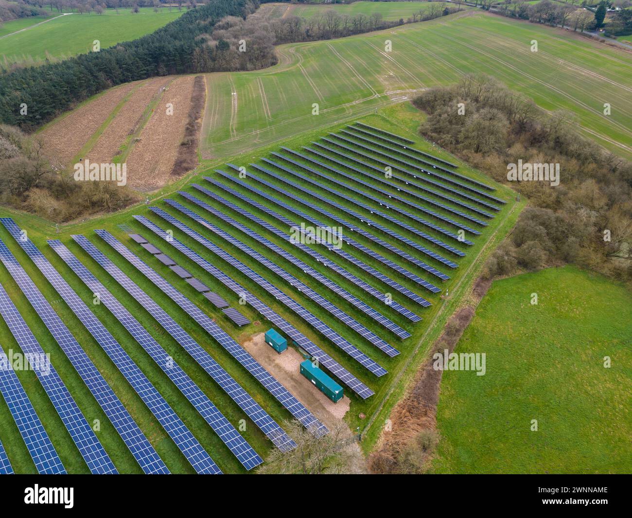 High-angle shot showcasing a vast array of solar panels amongst green ...