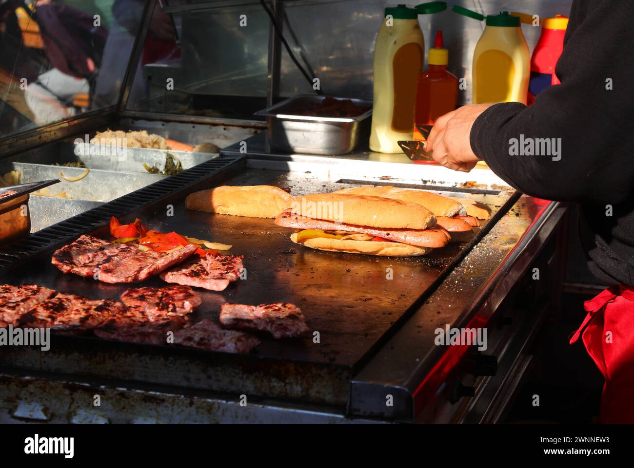 cook at counter of a street food truck preparing sandwiches filled with ...