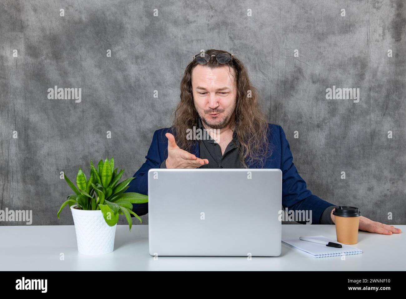 Professional male with long hair working diligently on a laptop in a ...