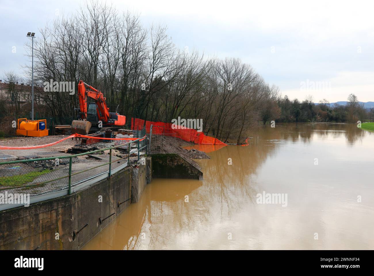red excavator on the embankment of the river in flood during the flood ...