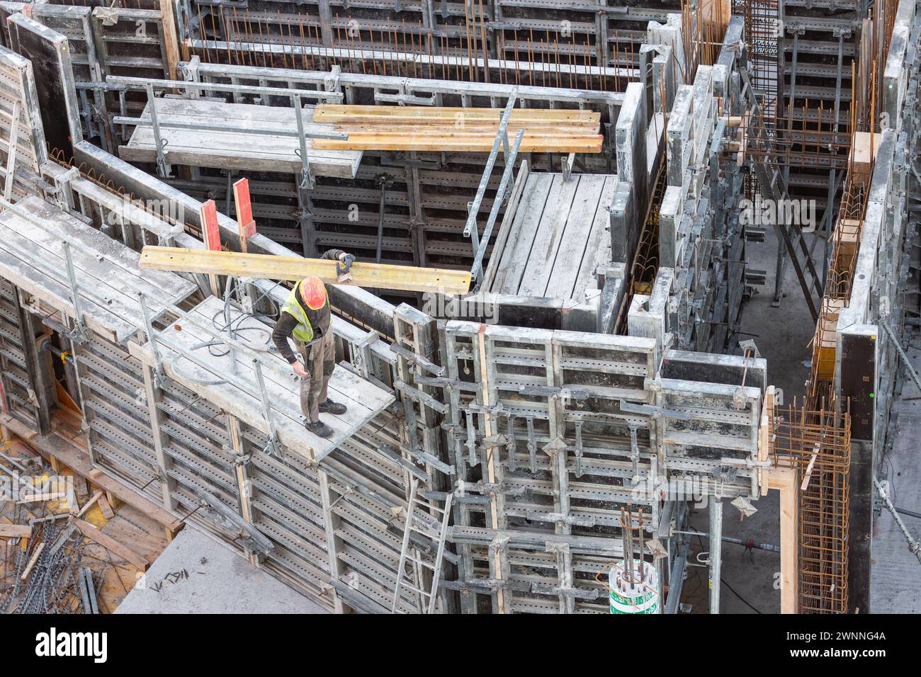 Worker carries wooden plank onto concrete formwork Stock Photo - Alamy