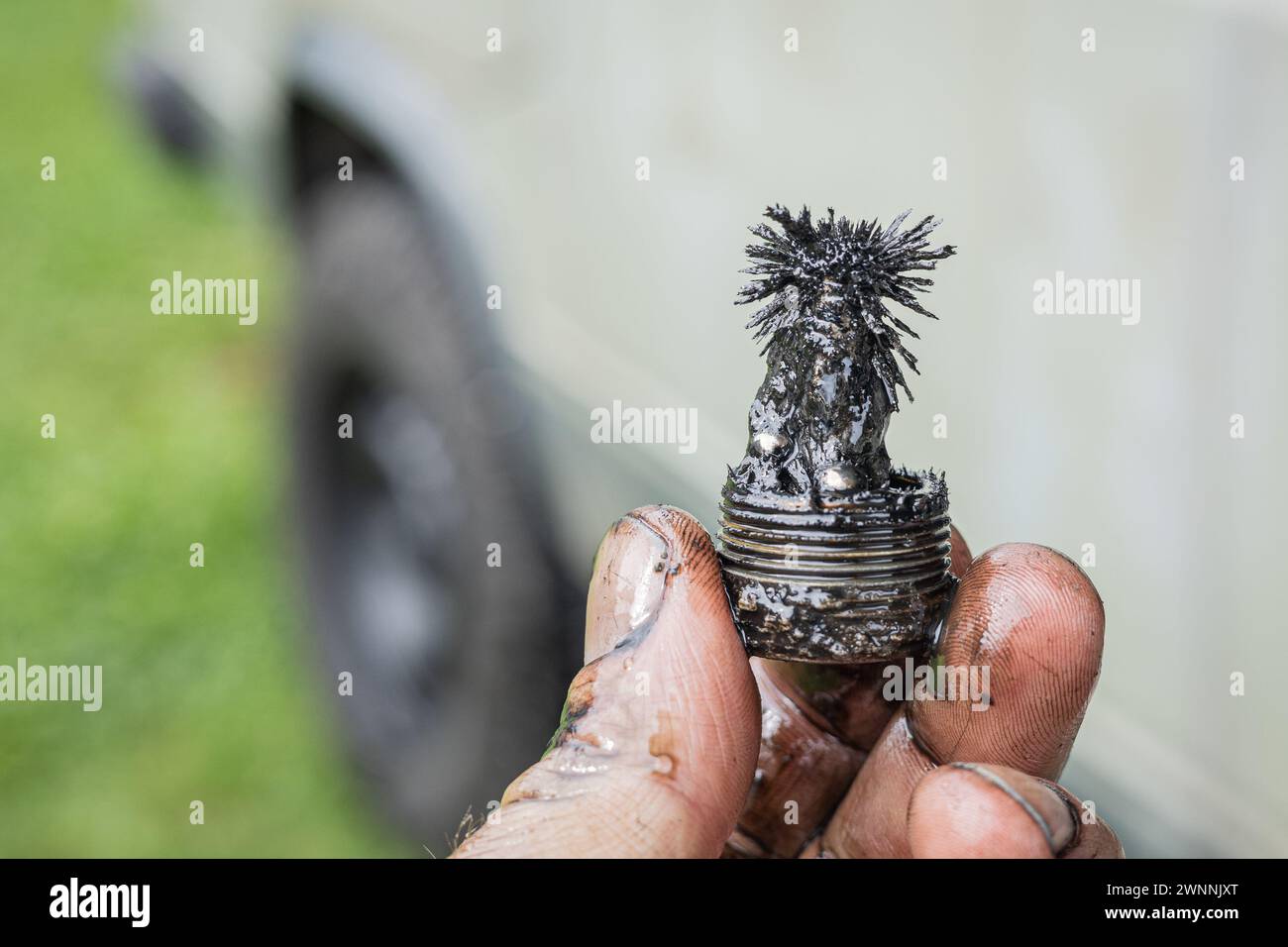 Man holding a magnetic plug or screw of a gearbox in hand, with visible ...