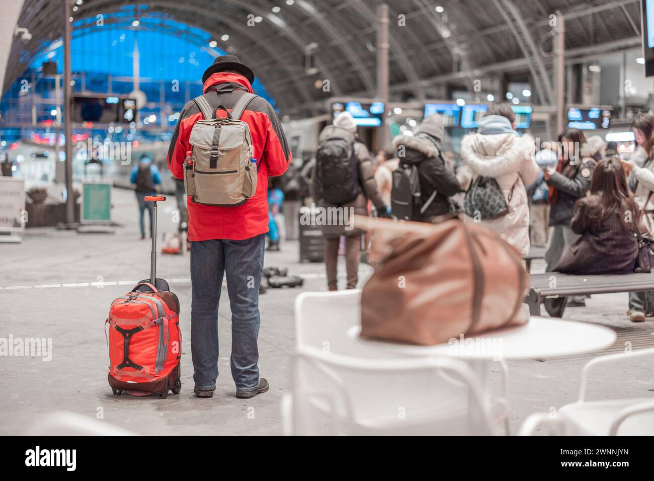 Unknown person with red jacket, backpack and a bag is waiting for a ...