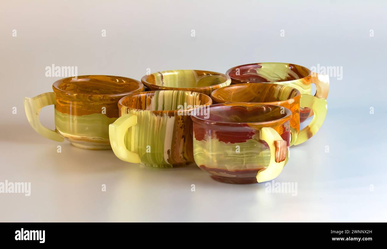 Empty cups made of multi-colored onyx in yellow-orange tones on a white ...