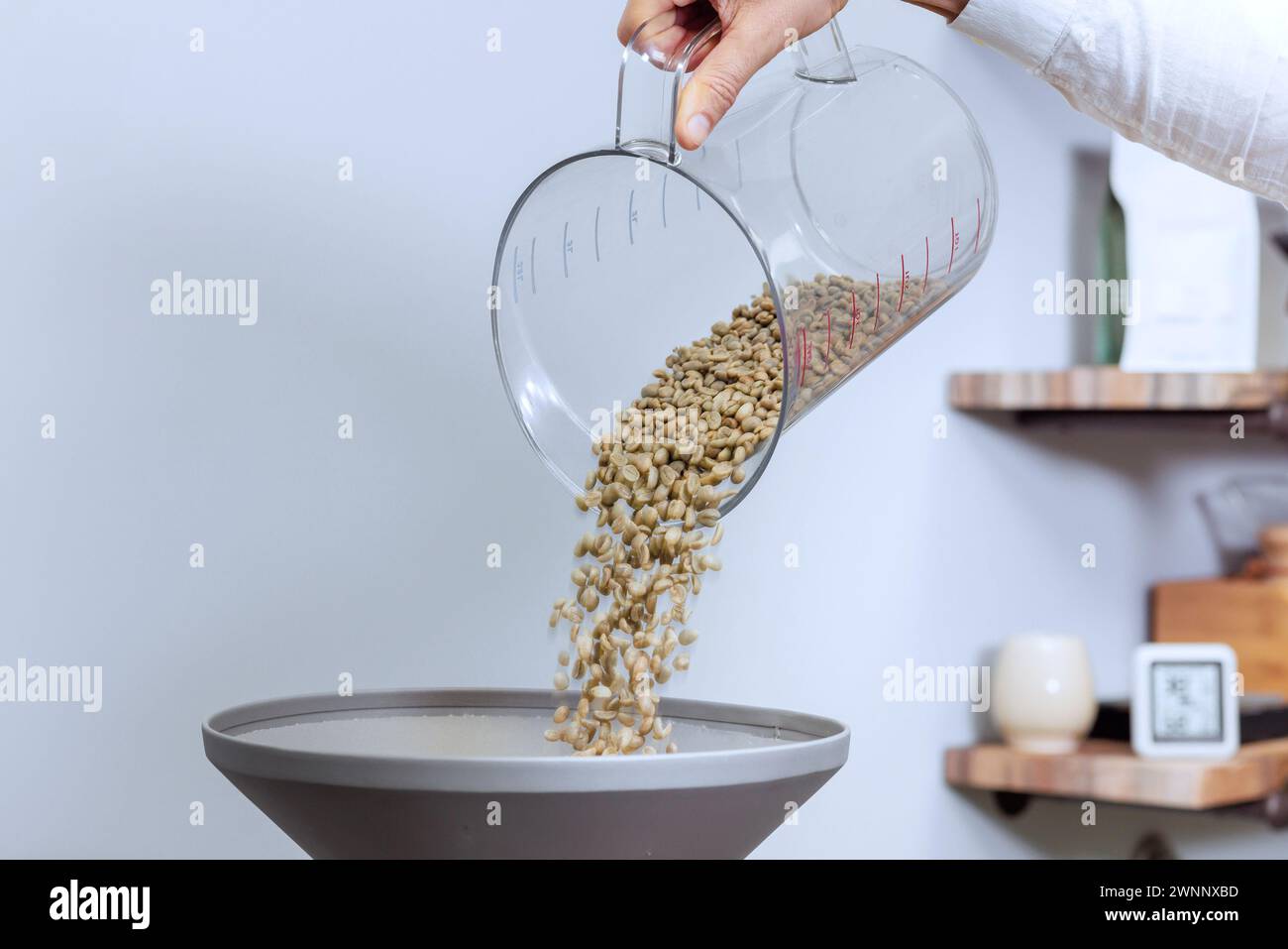 Pouring raw coffee beans into oven for roasting Stock Photo - Alamy
