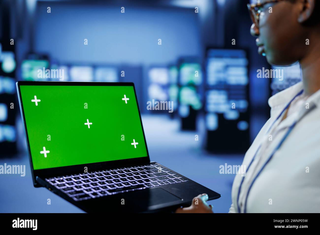 Programmer in server room uses green screen laptop to future proof network from downtimes and ...